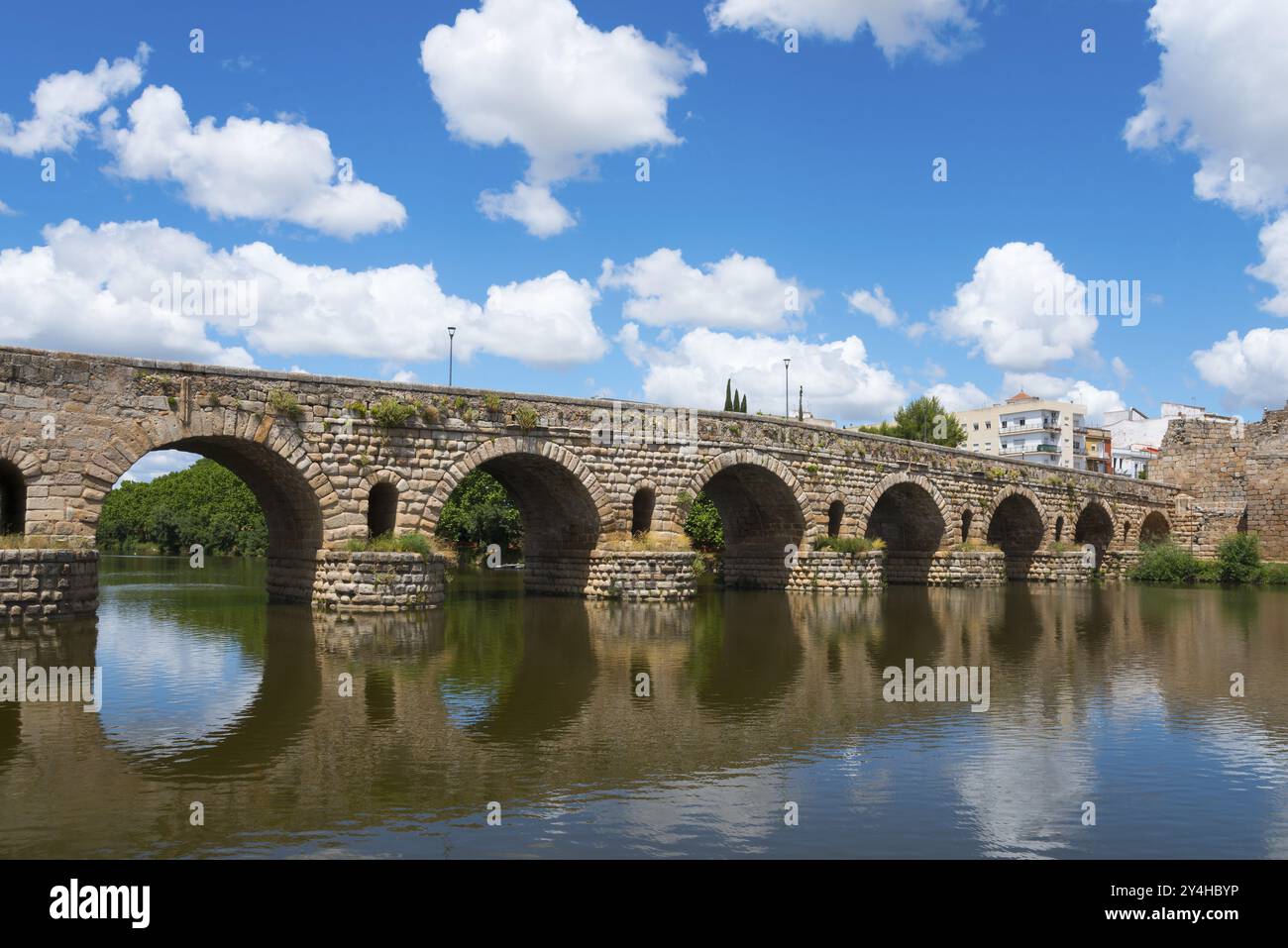 Ancient stone bridge with reflections in the river water, under blue ...