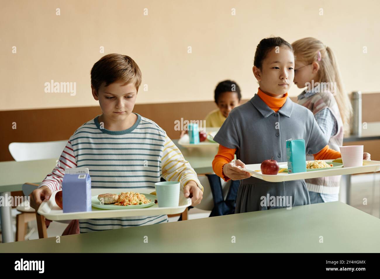 Medium shot of young boy and Central Asian girl on break, holding trays ...