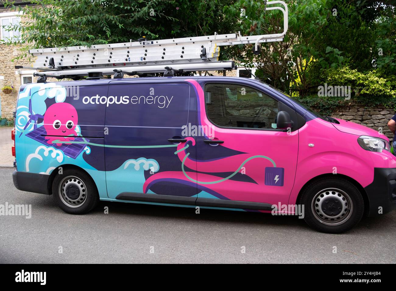 Side view of an Octopus Energy van and logo with extension ladders on roof parked on an ...