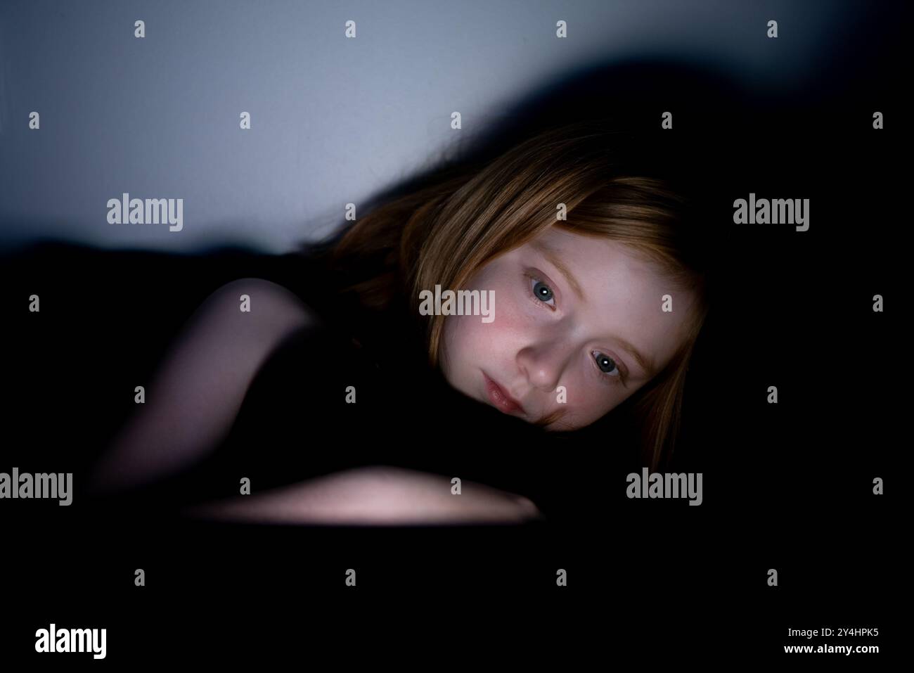 Low-light portrait of a girl using a screen at night, with blue light ...