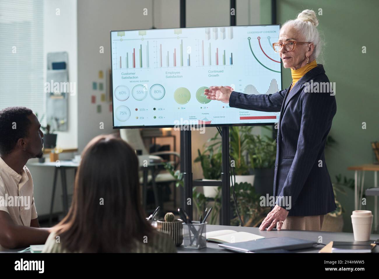 Senior businesswoman presenting data analysis on large screen to ...