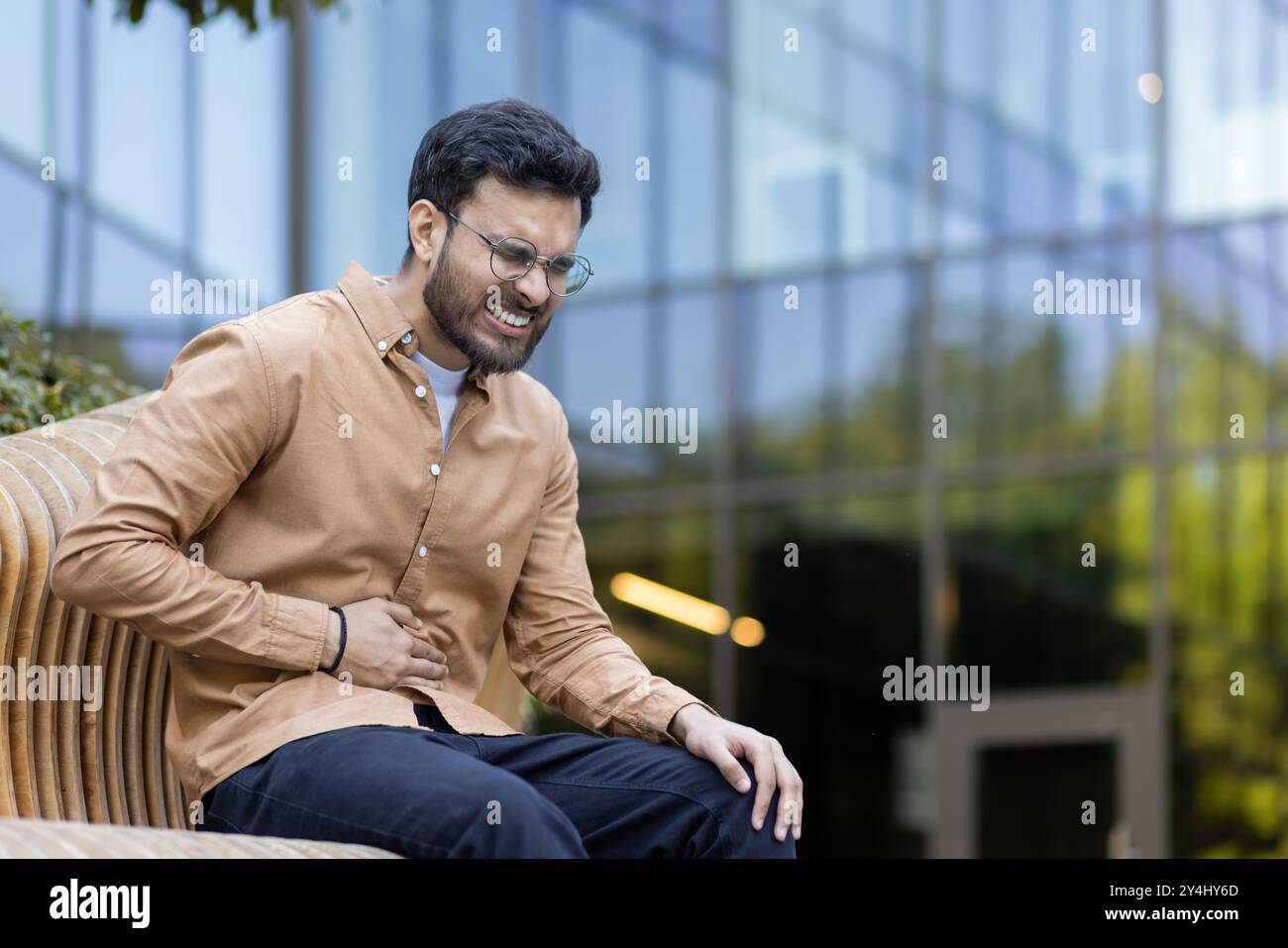 Man in casual attire sits on bench outdoors showing expression of ...