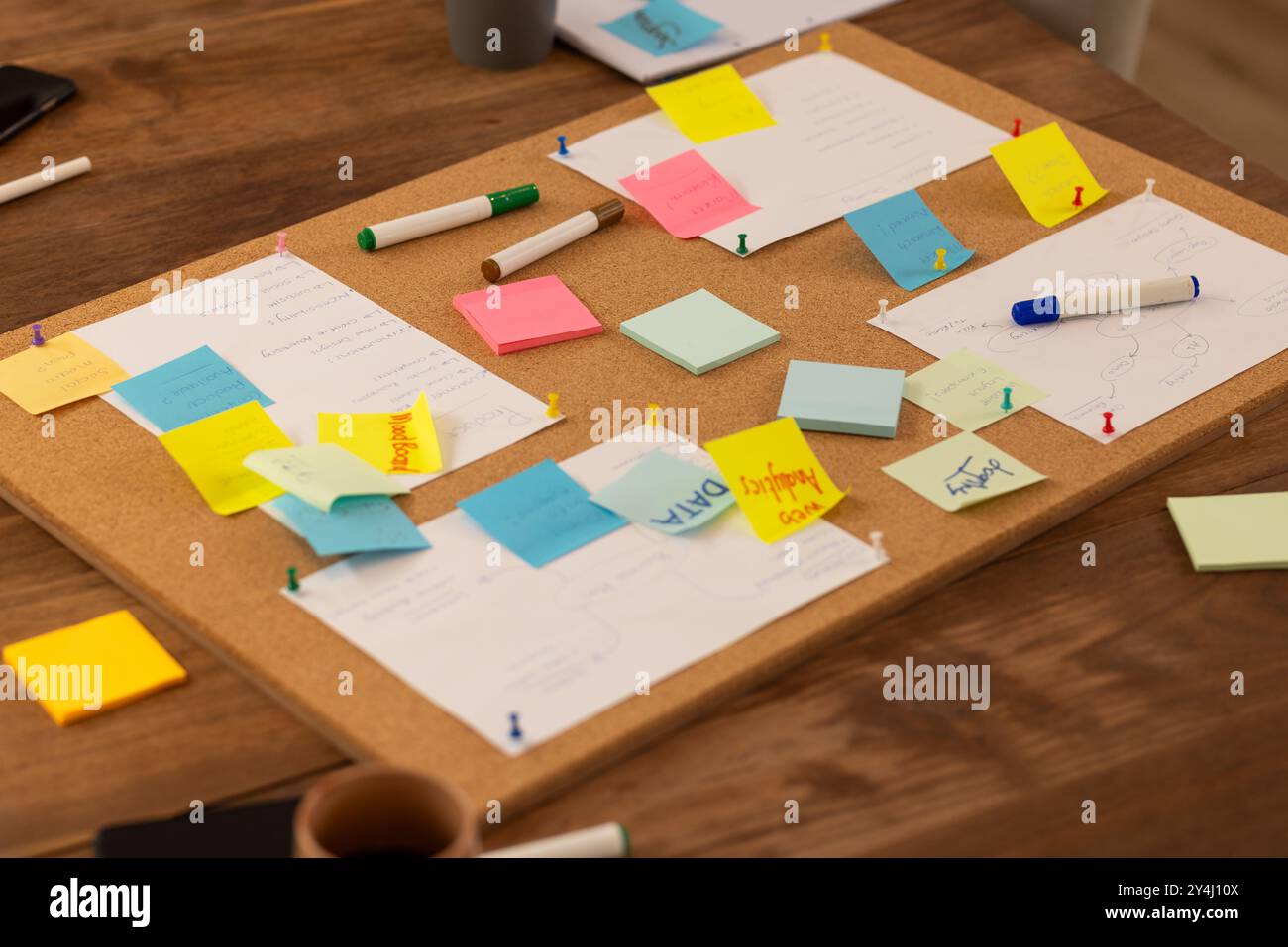 Brainstorming ideas, using sticky notes and markers on corkboard in ...