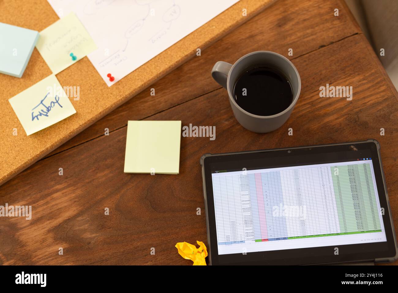 Using tablet with spreadsheet, person working at desk with coffee and ...