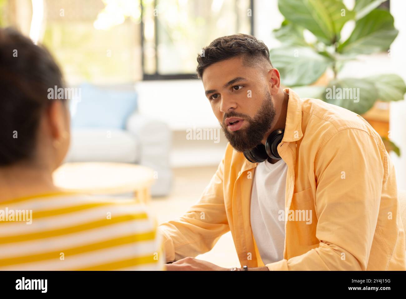 Wearing headphones and yellow shirt, man engaging in conversation with ...