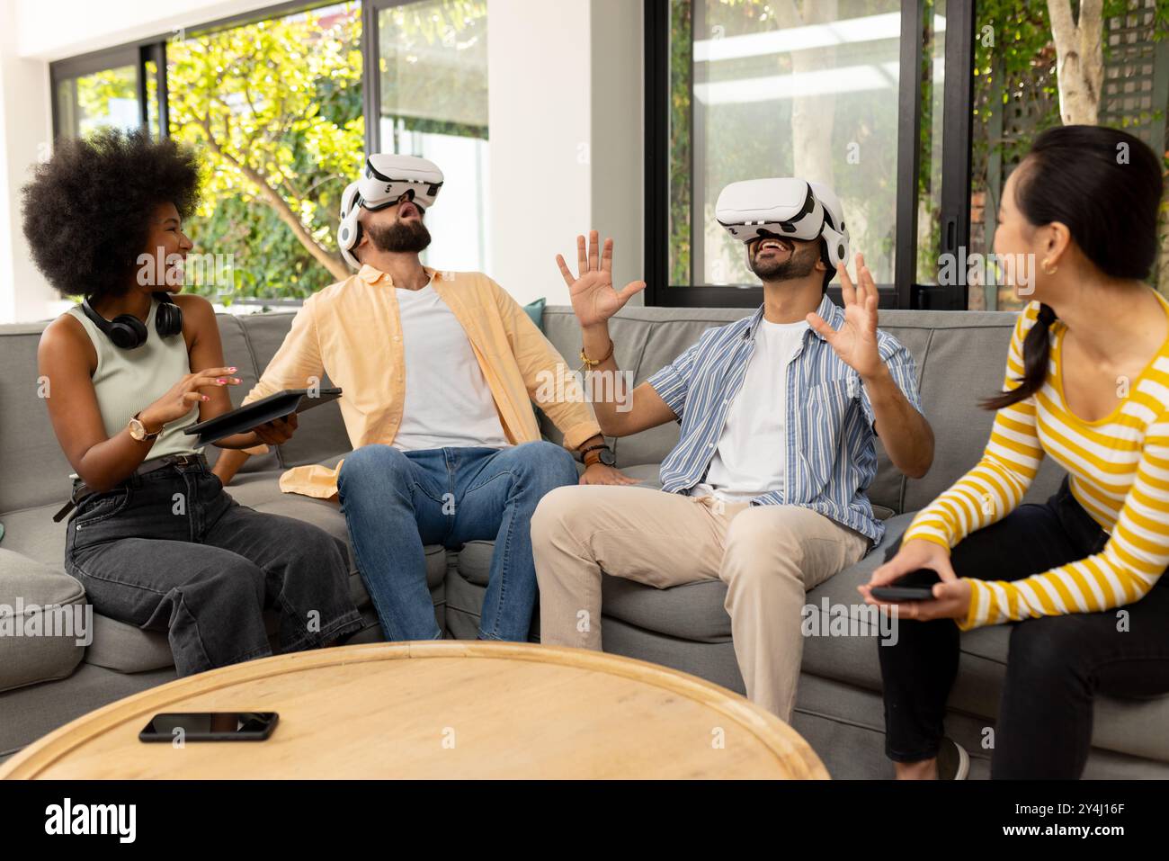 Using VR headsets, diverse friends enjoying virtual reality experience ...