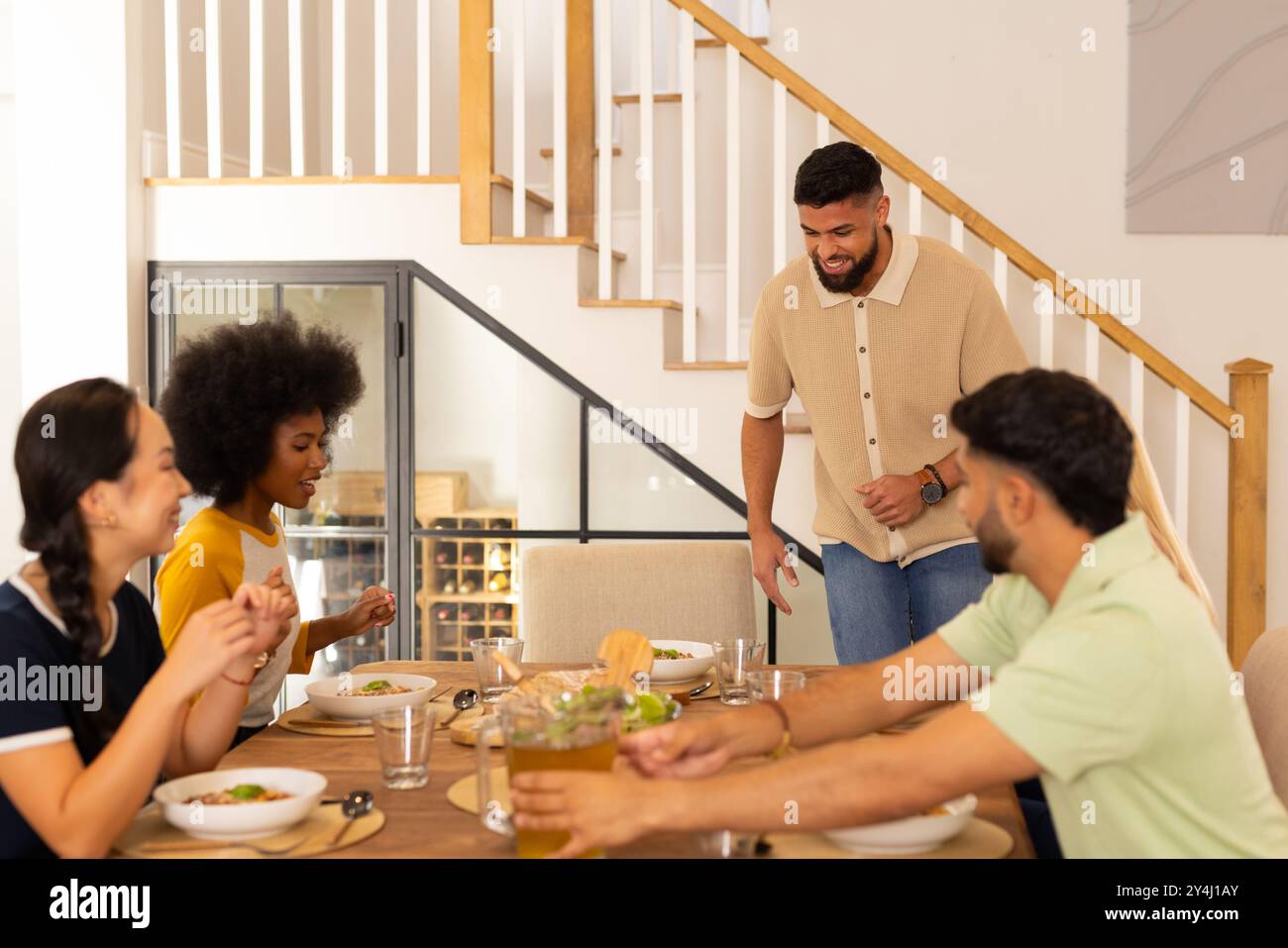 Friends enjoying meal together at dining table, laughing and ...