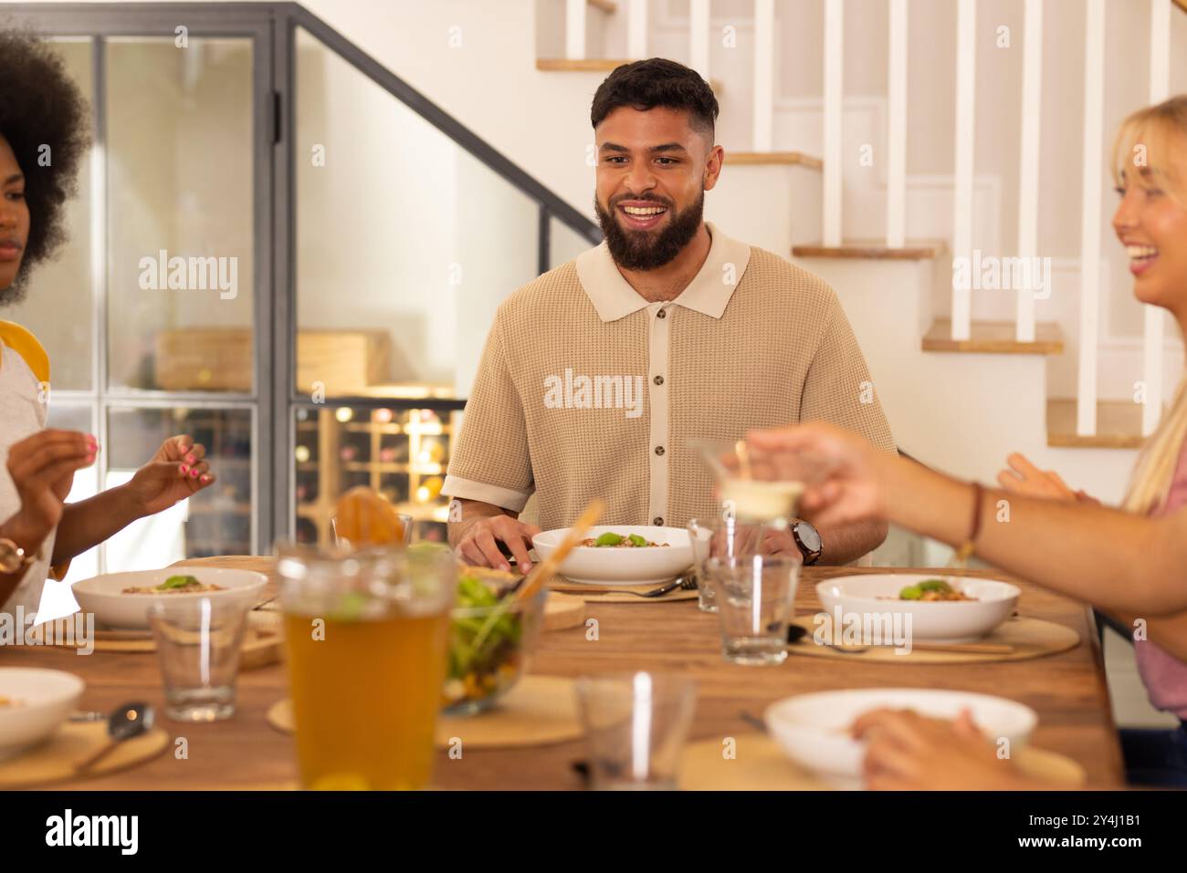 Friends enjoying meal together, smiling and chatting around dining ...