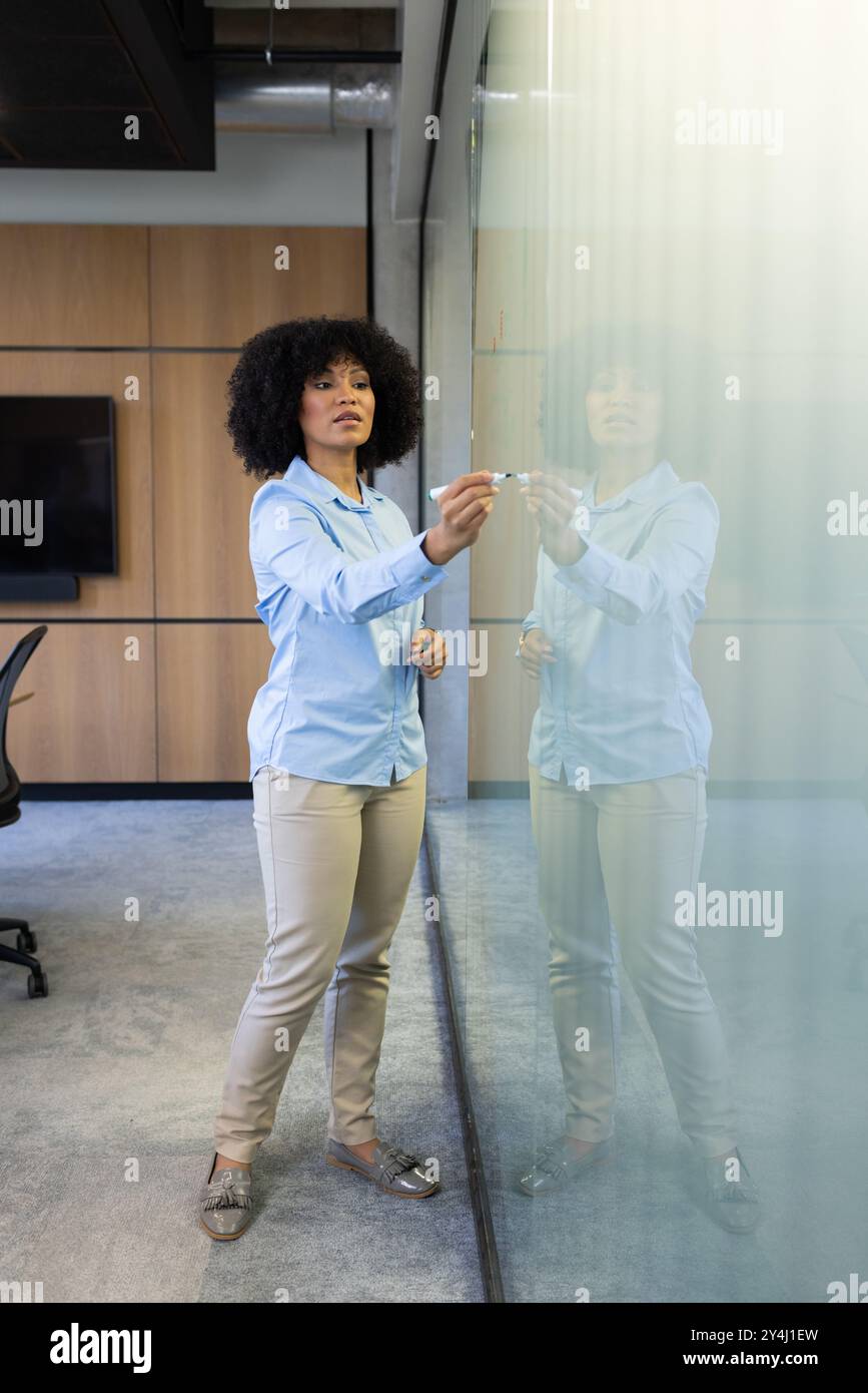 Writing on glass board, businesswoman presenting ideas in modern office ...