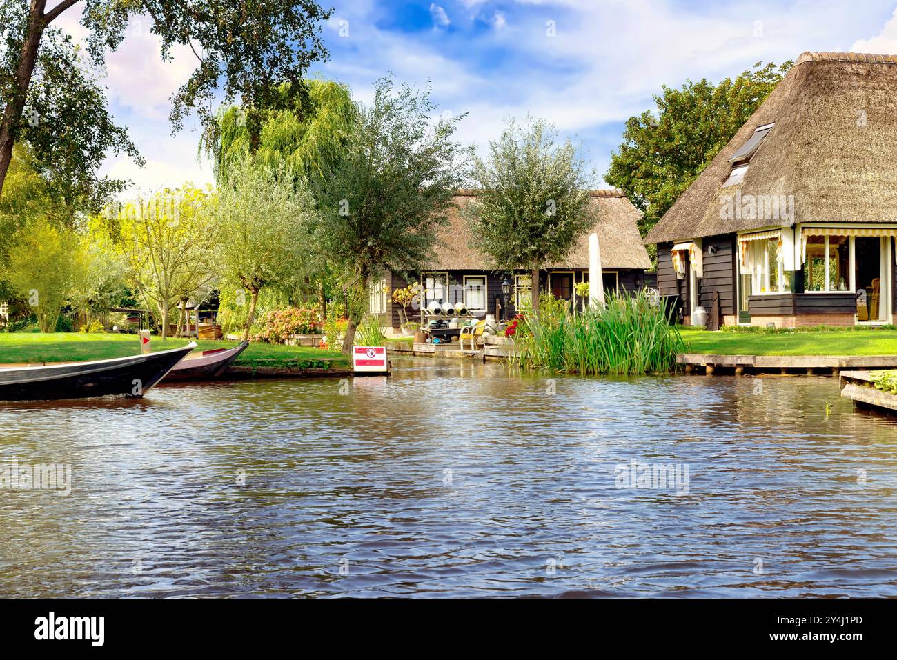 A tranquil riverside village with thatched-roof cottages and boats ...