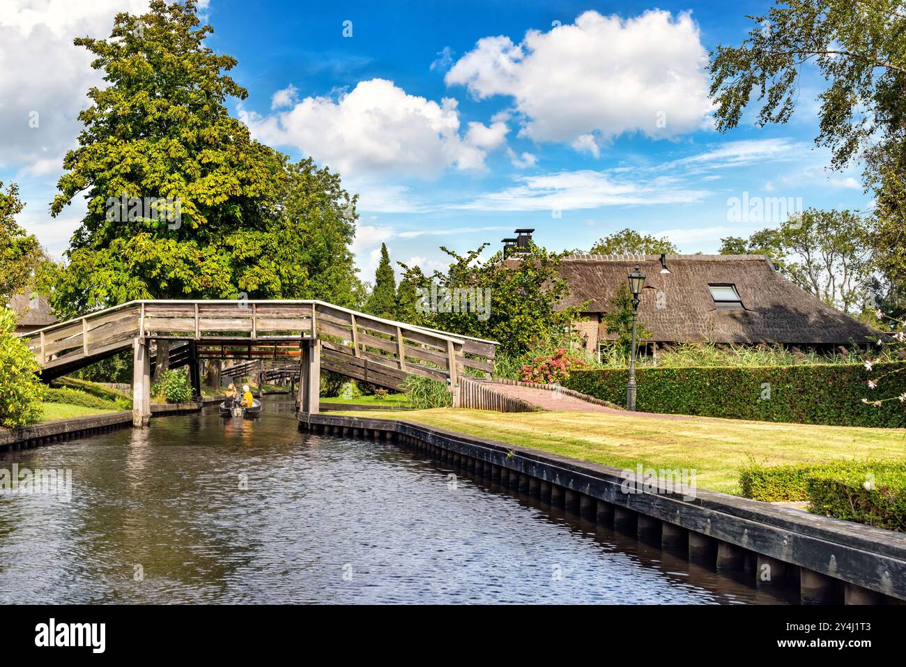 A tranquil riverside village with thatched-roof cottages and boats ...