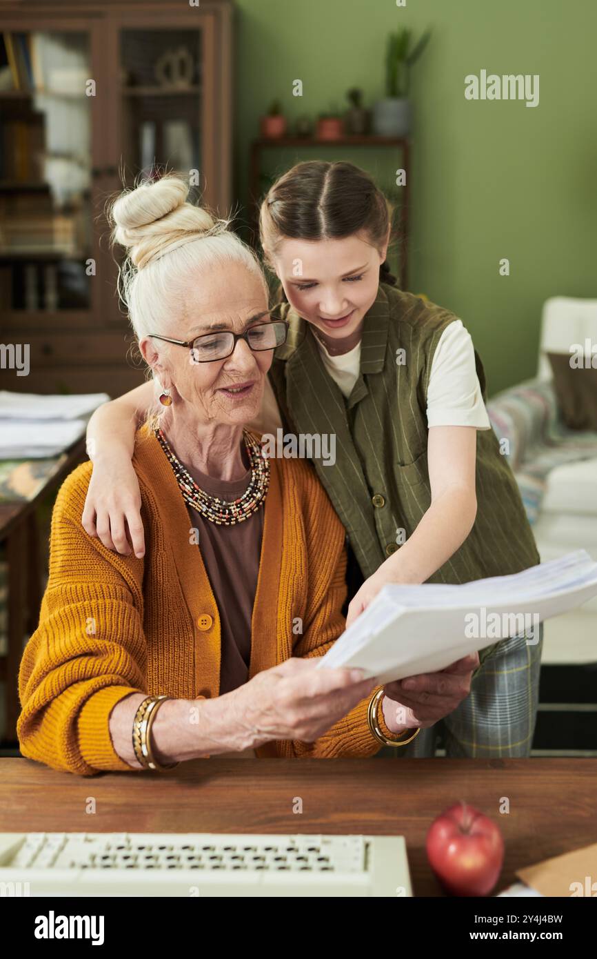 Elderly woman and young girl engaging with documents at home, showing ...
