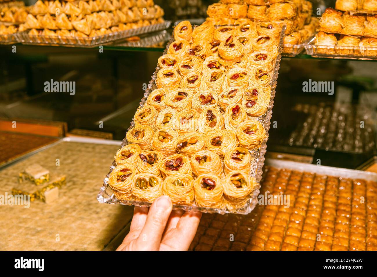 Hand holding tray of Middle Eastern traditional pastries, displaying a ...