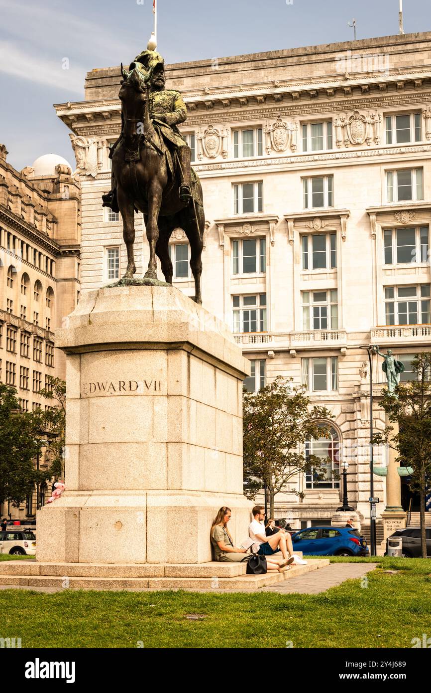a couple of people reading books sat on the steps under the statue of ...
