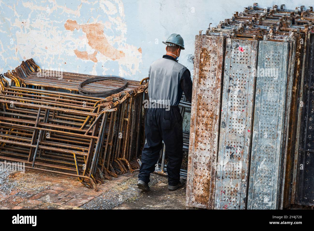 Brazilian construction worker organizing scaffolding parts in a ...