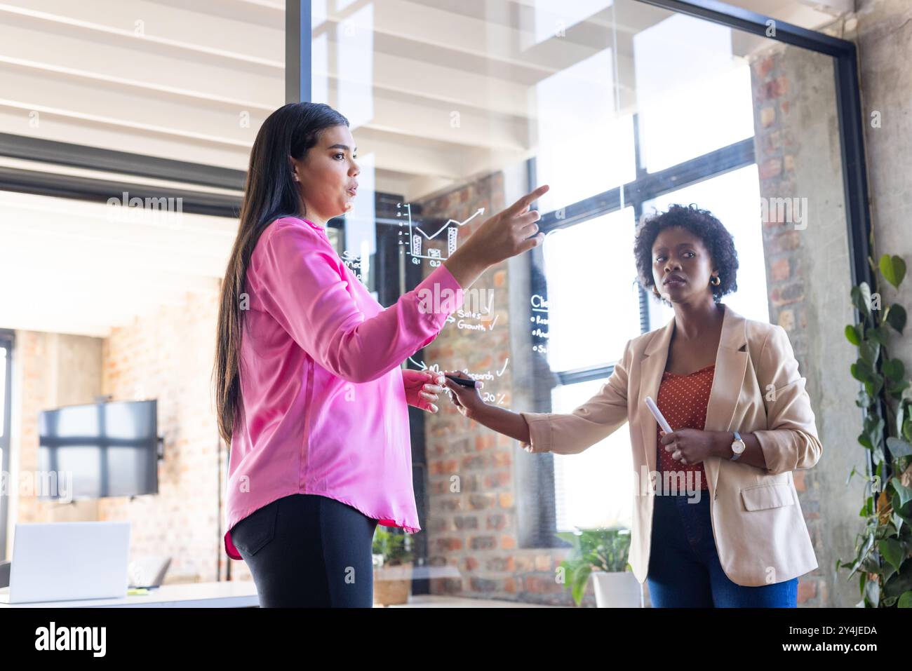 Discussing business strategy, two women collaborating in modern office ...