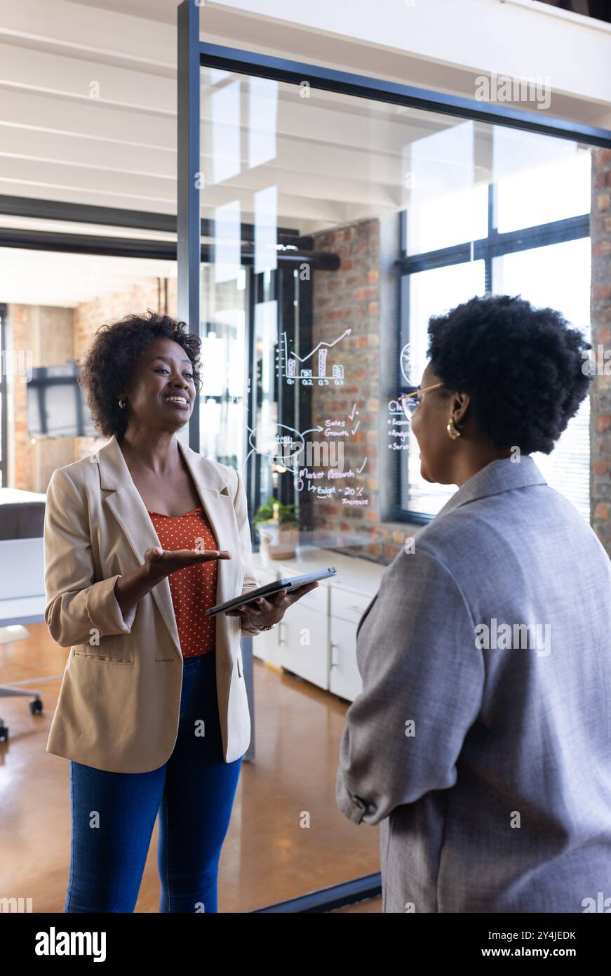 Discussing business strategy, two women collaborating in modern office ...