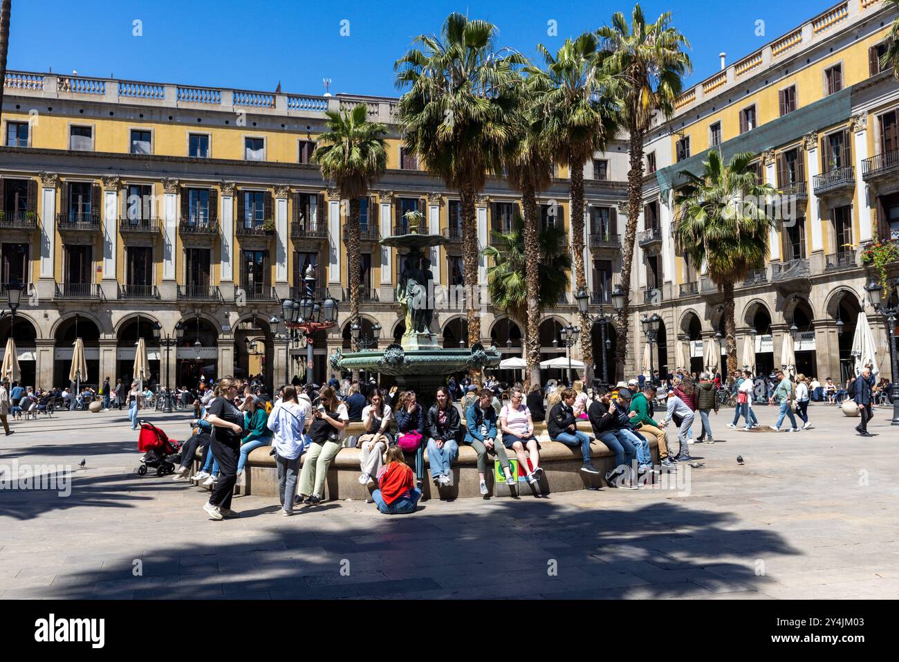 Visitors to Placa Real in Barcelona, Spain sit around a fountain in the ...