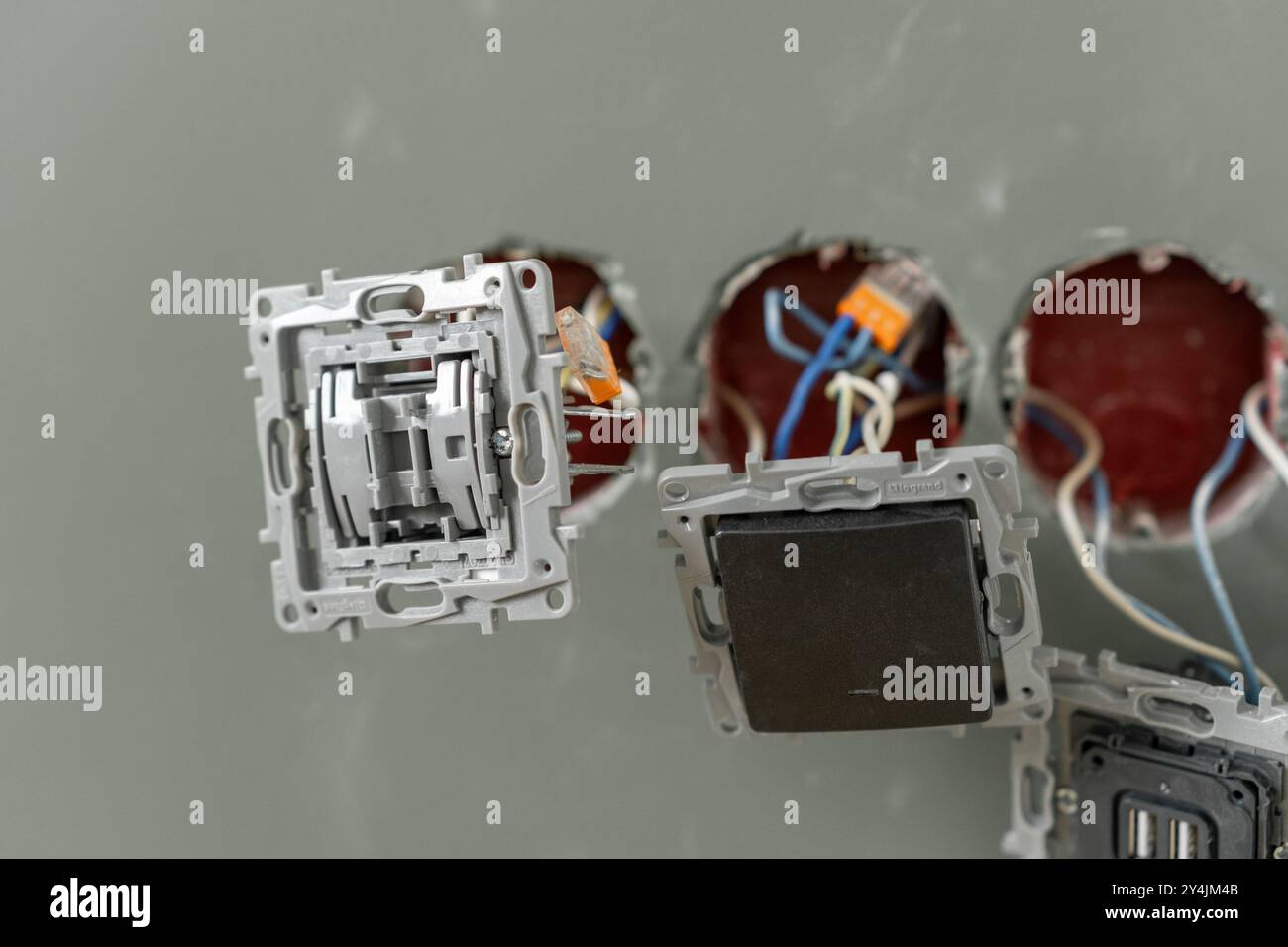 Technicians are seen installing electrical switch plates in wall ...