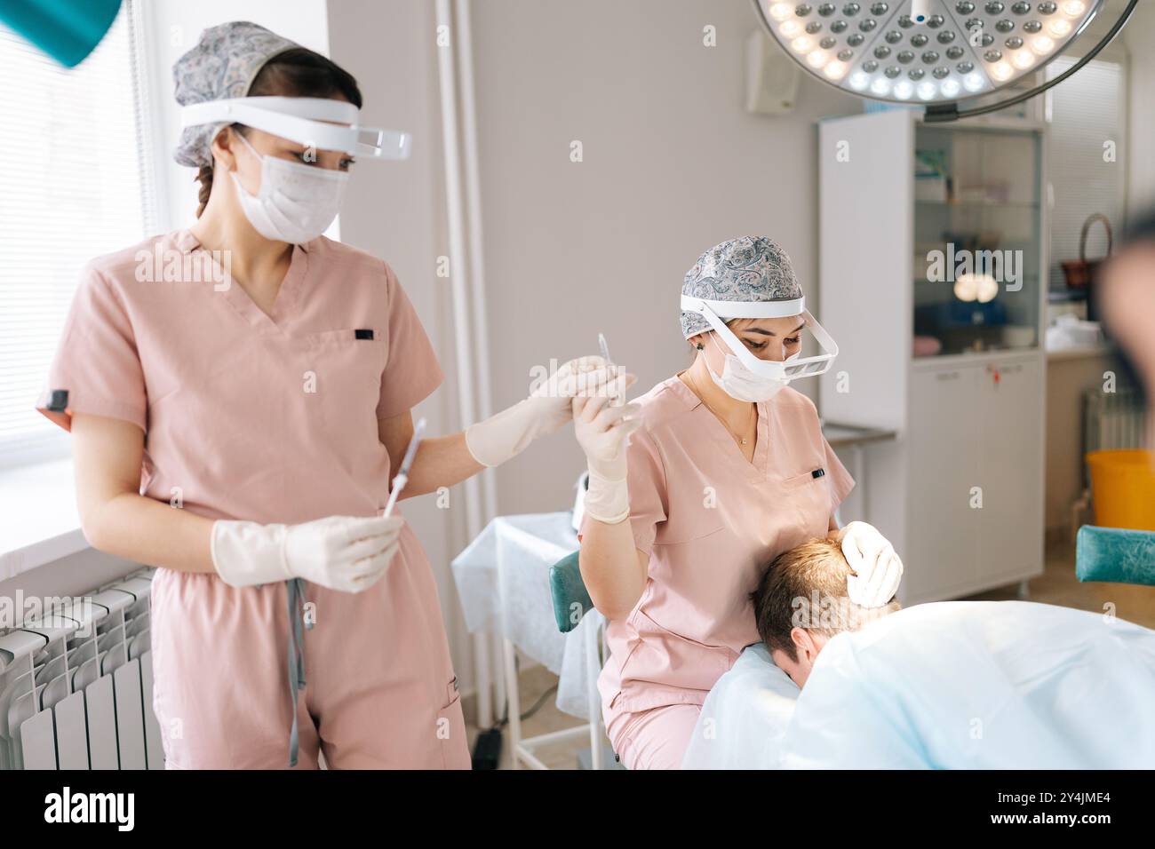 Trichologist performing local anesthesia to back of head in recipient ...