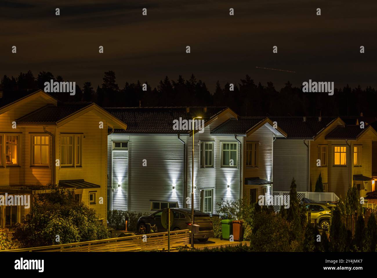 Night suburban neighborhood view with modern homes illuminated by warm ...