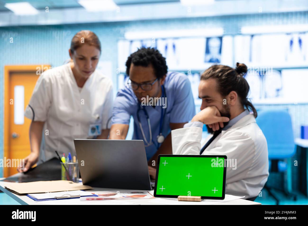 Group of doctors consulting hospital records next to chroma key display ...