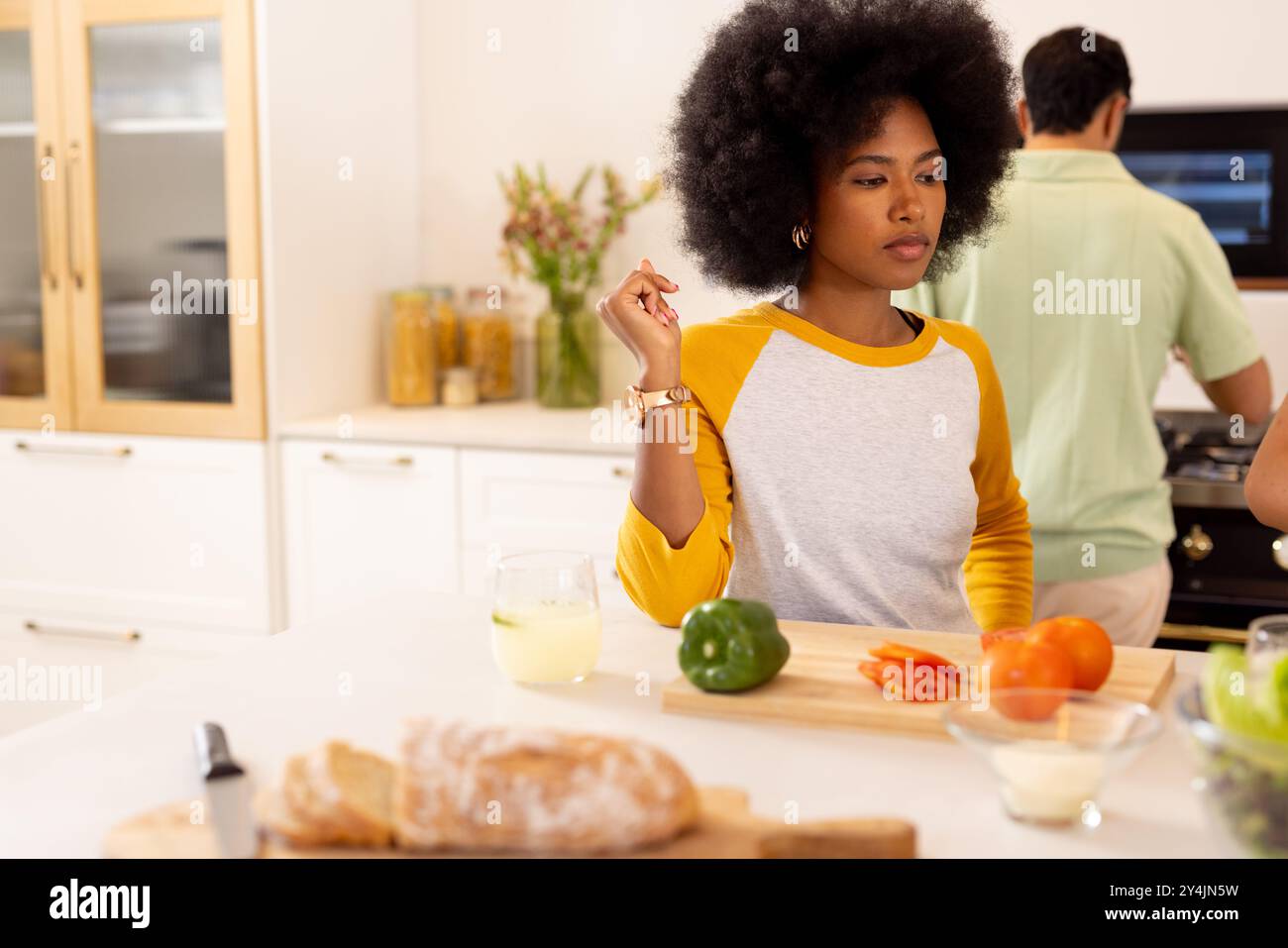 Preparing vegetables in kitchen, woman with afro hairstyle focusing on ...