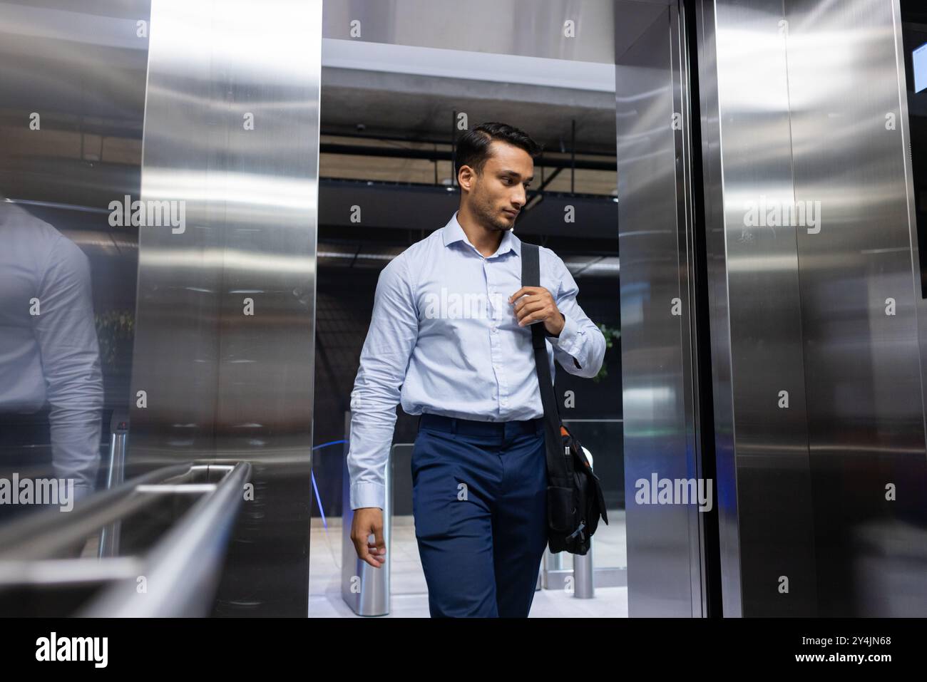 Entering elevator, businessman carrying shoulder bag, heading to office ...