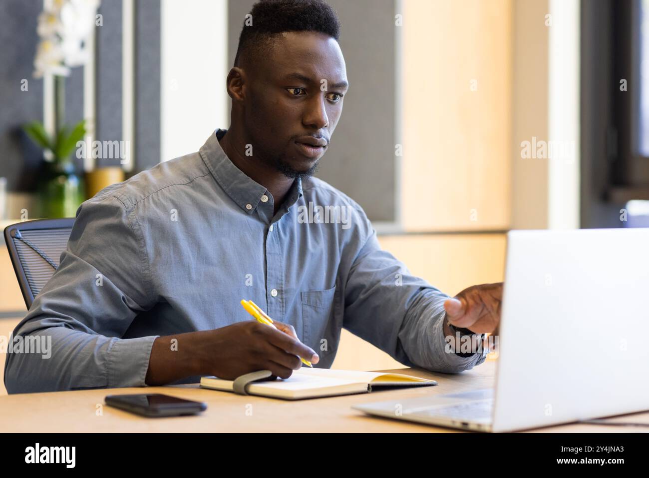 Working on laptop, man taking notes in office, focusing on task Stock ...