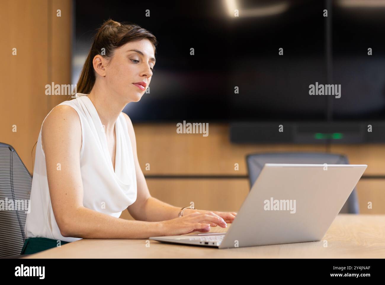 Working on laptop, businesswoman focusing on tasks in modern office ...