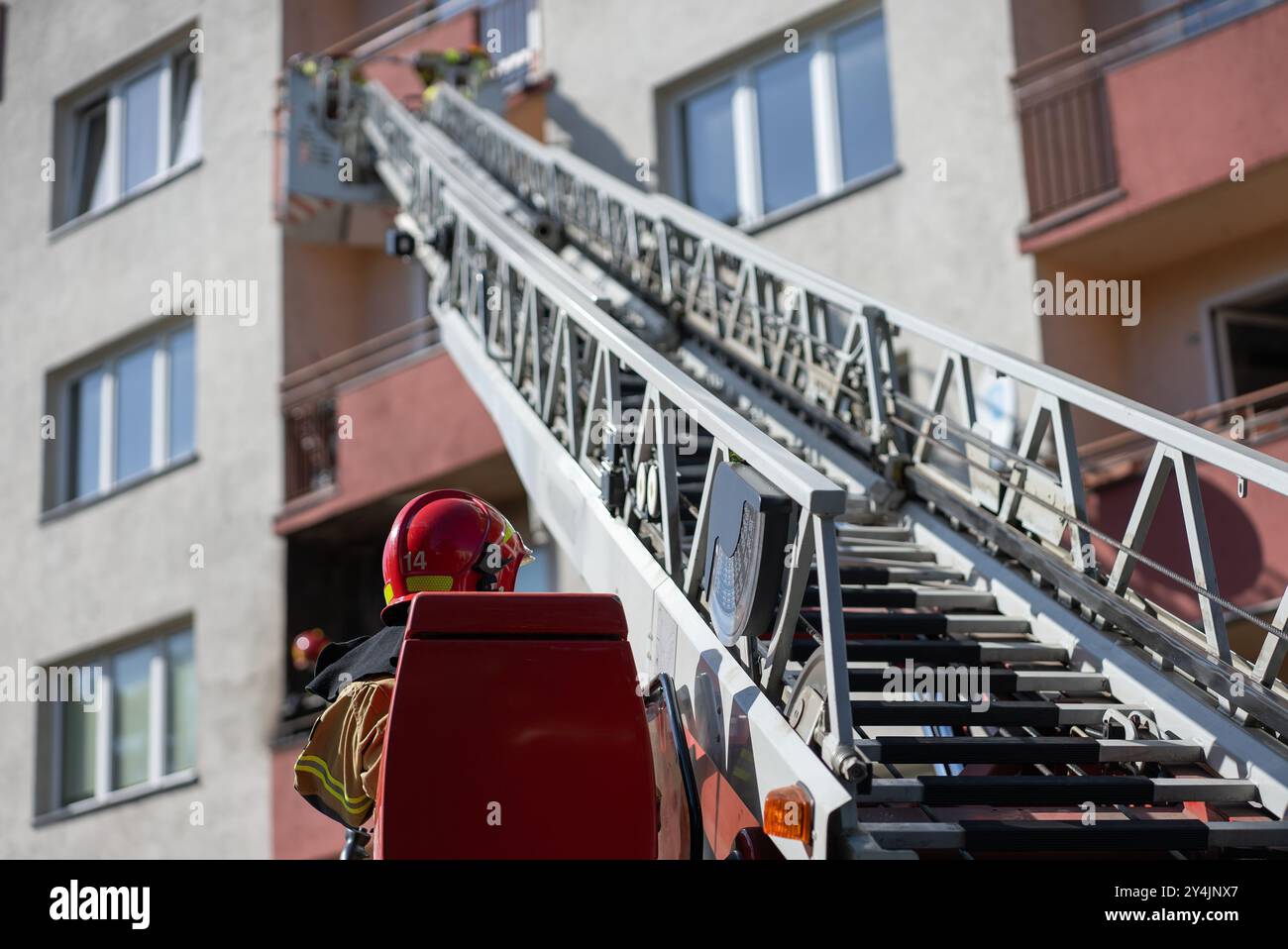 operator of fire truck with extended elevated ladder reaches up to ...