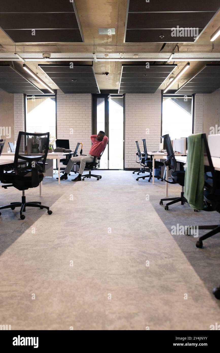 Relaxing in office, african american man leaning back in chair in ...