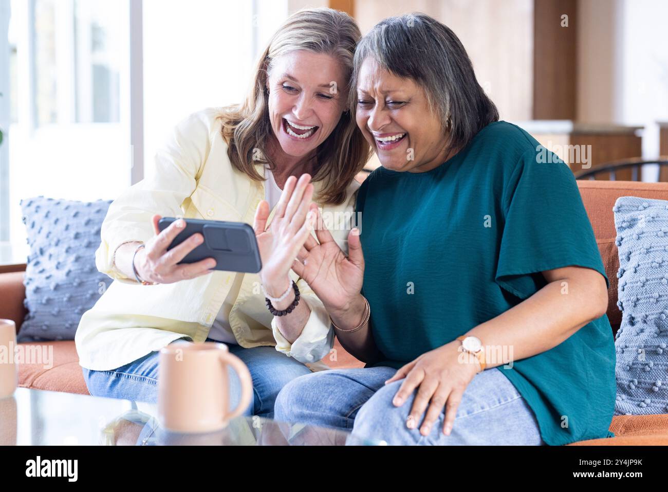 At home, smiling senior multiracial female friends video calling on ...