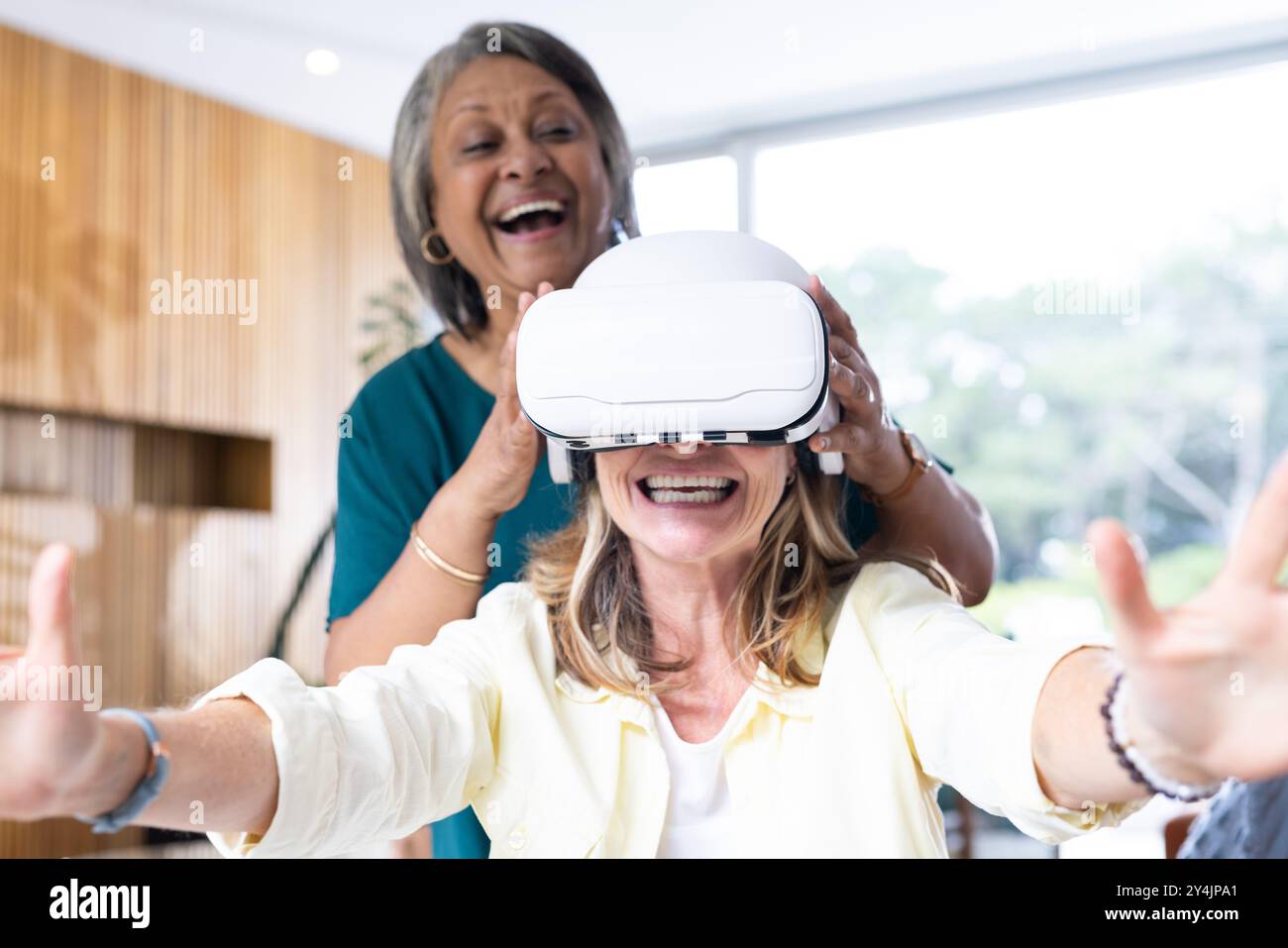 At home, using vr headset, senior multiracial female friends enjoying ...