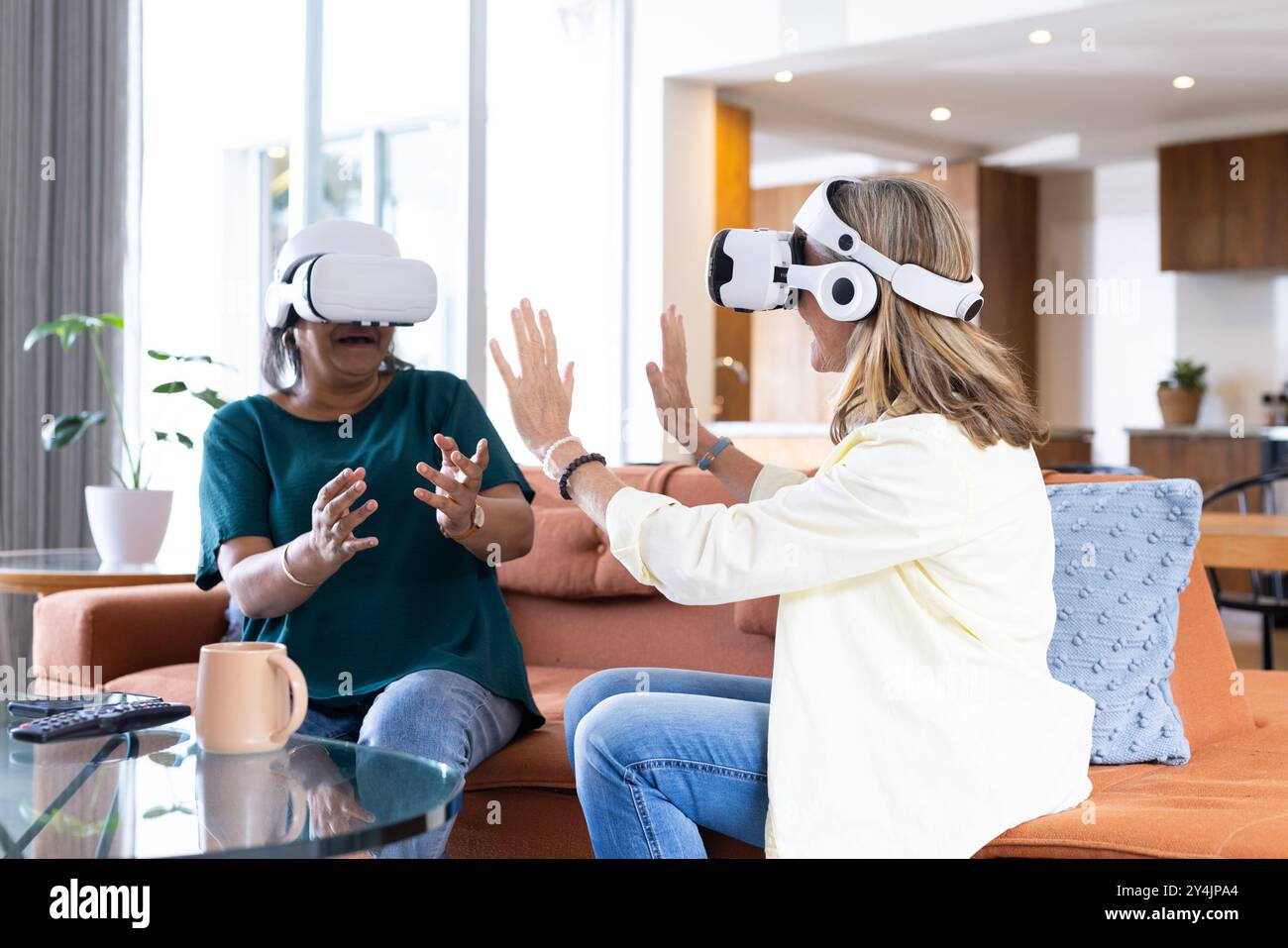 At home, using vr headsets, two senior multiracial female friends ...