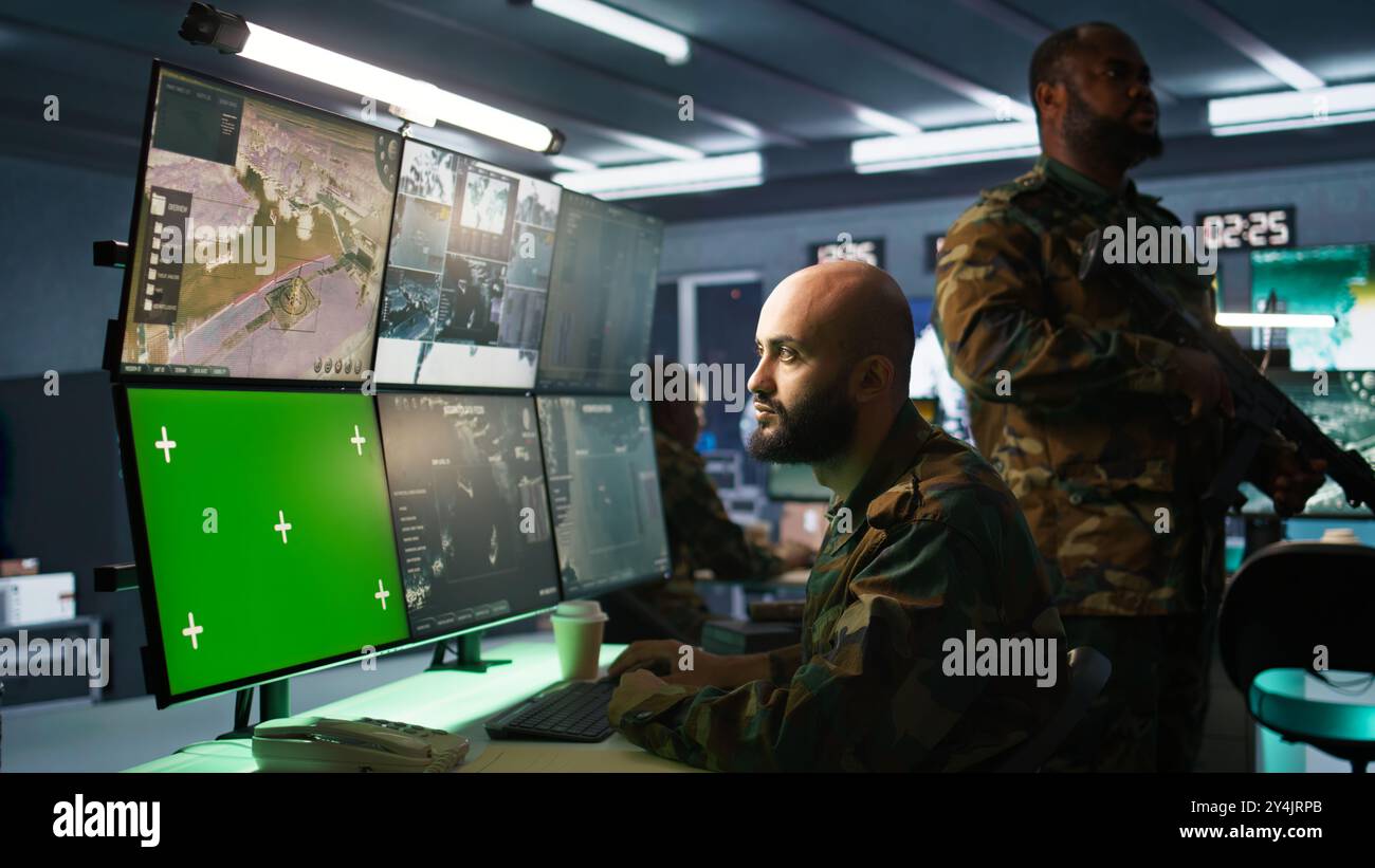 Army soldier looking at chroma key screens in command center housing ...