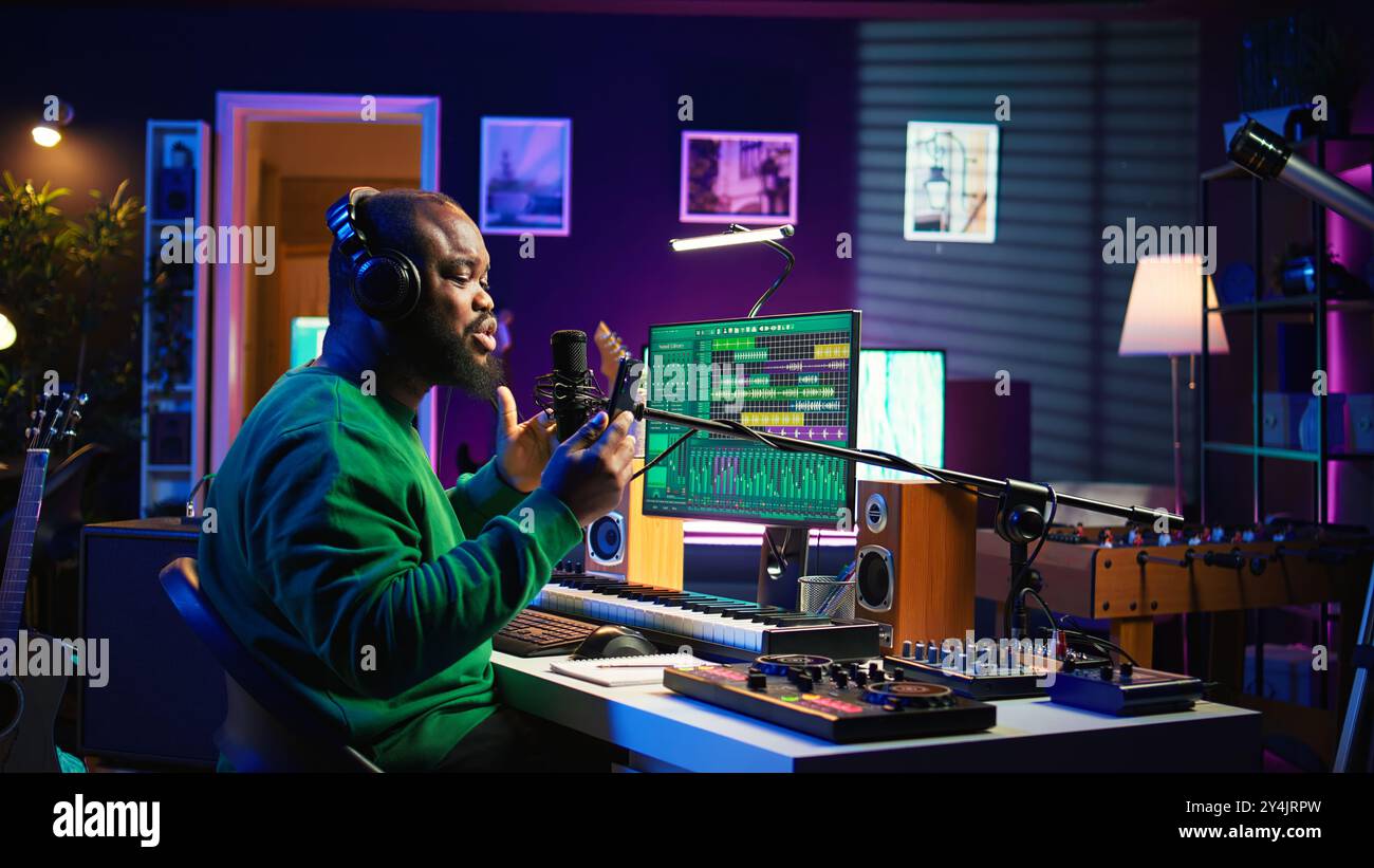 Male composer recording his melody on microphone in home studio, singing a song of his own ...