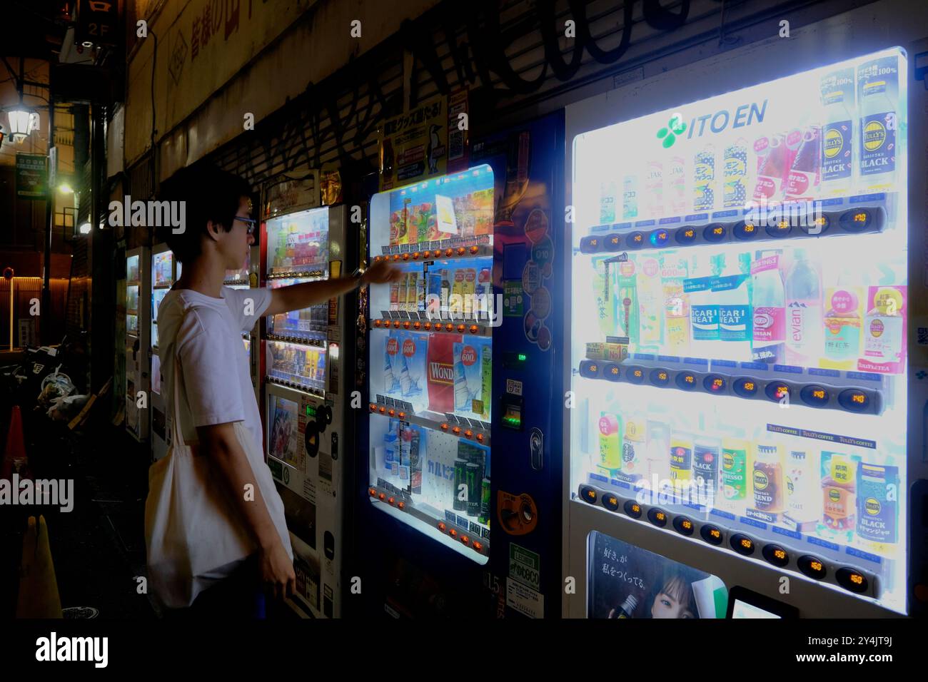 Young man purchasing soft drink from a vending machine on sidewalk in ...