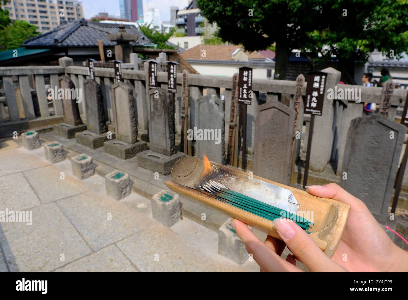 A visitor holding burning incense offering to the graves of 47 Ronin of ...
