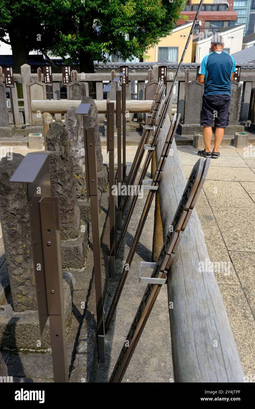Visitor offering incenses to the graves of the 47 Ronin of Akō incident ...
