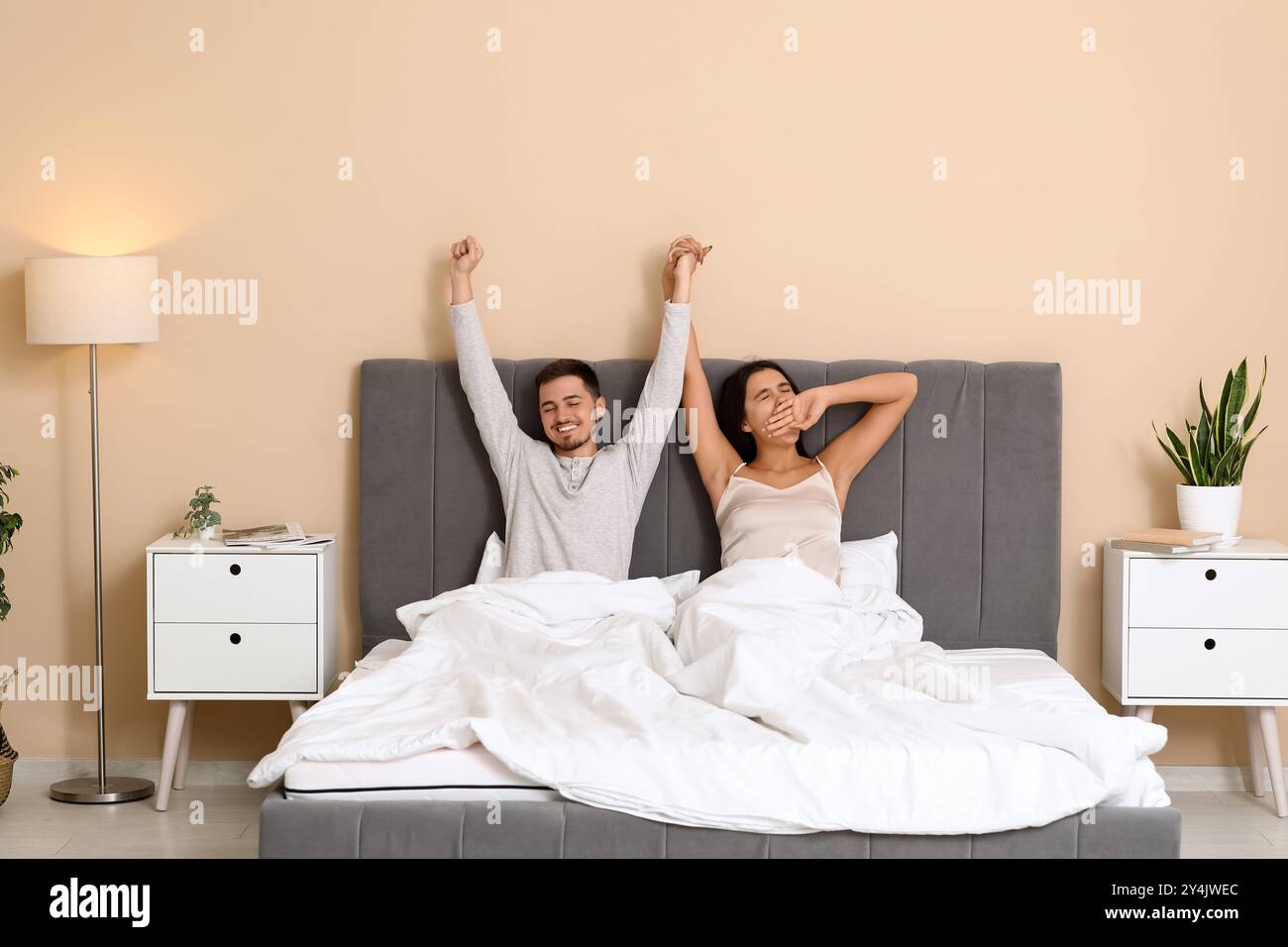 Young couple waking up in bedroom Stock Photo - Alamy