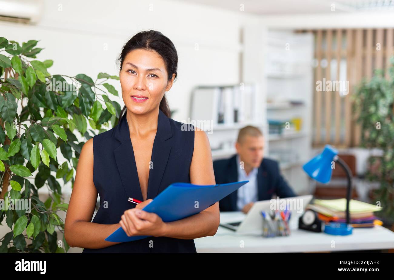 Female administrative secretary standing in office with folder of ...