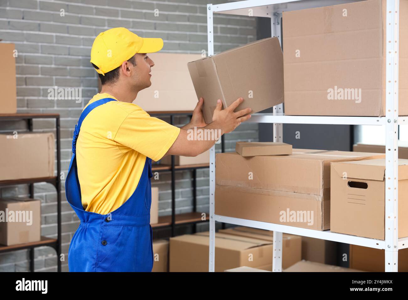 Delivery man taking parcel box from shelf in warehouse Stock Photo - Alamy