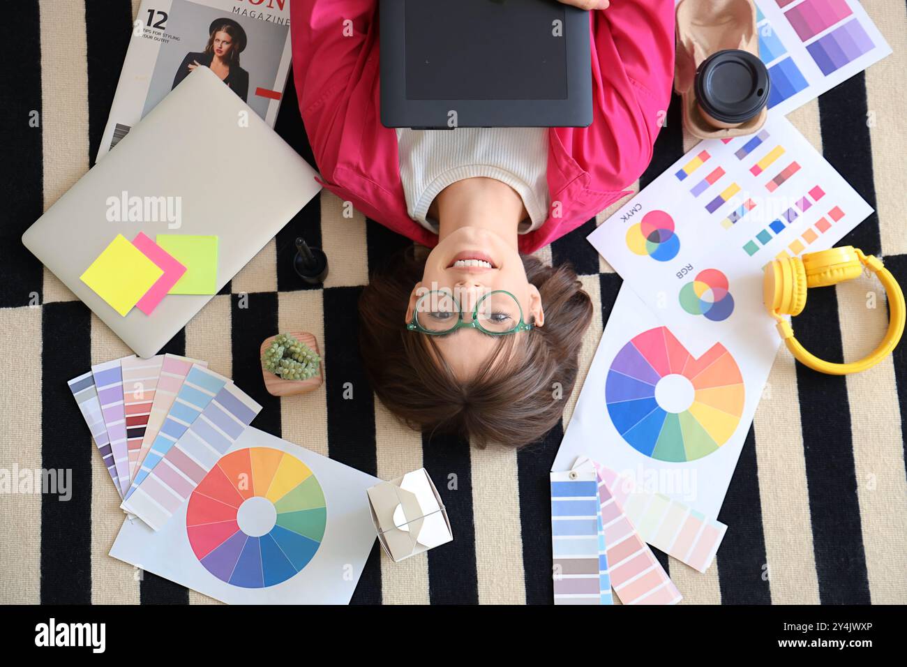 Female graphic designer with tablet and color palettes lying on carpet ...