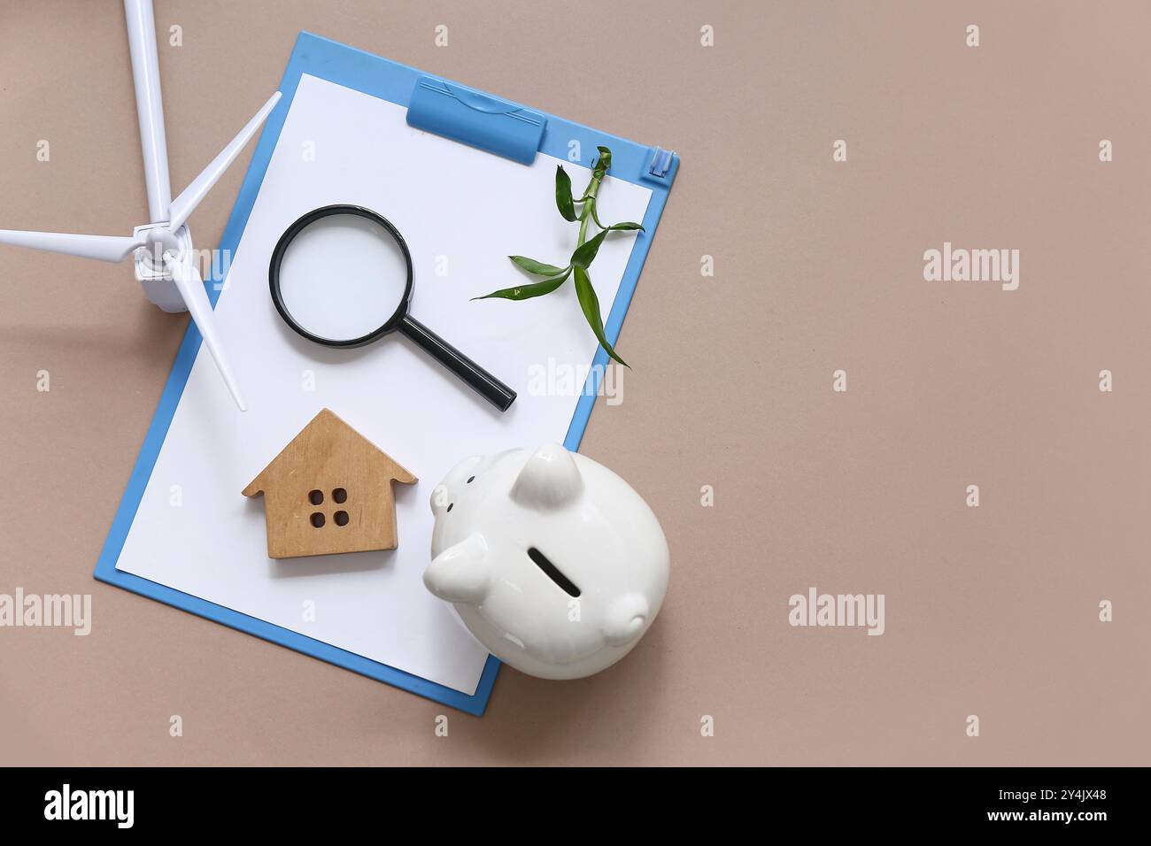 Clipboard with plant, magnifier, house figure, piggy bank and wind ...