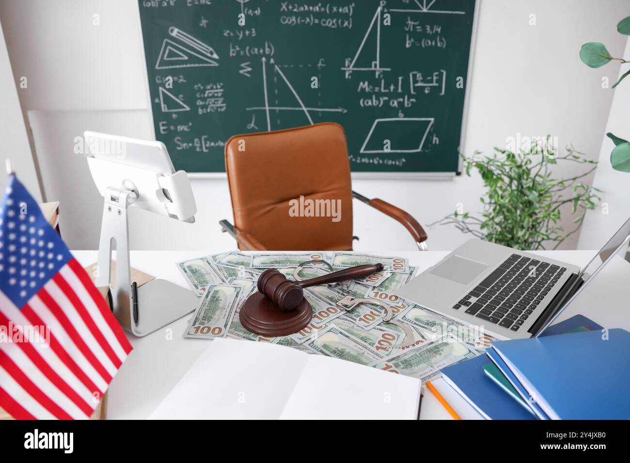 Teacher's desk with money, handcuffs and judge's gavel in classroom ...