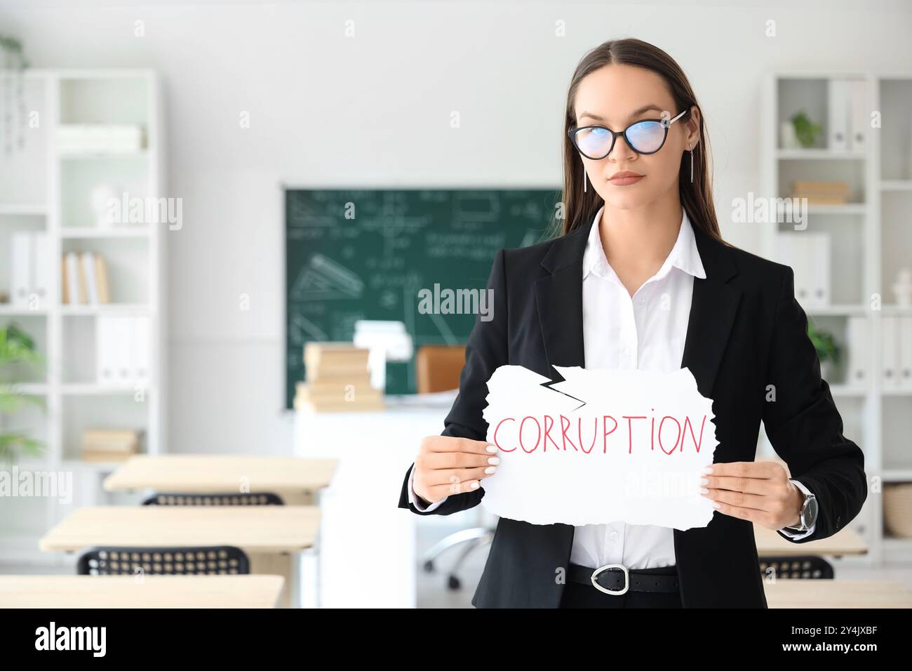 Female teacher holding paper with word CORRUPTION in classroom Stock ...
