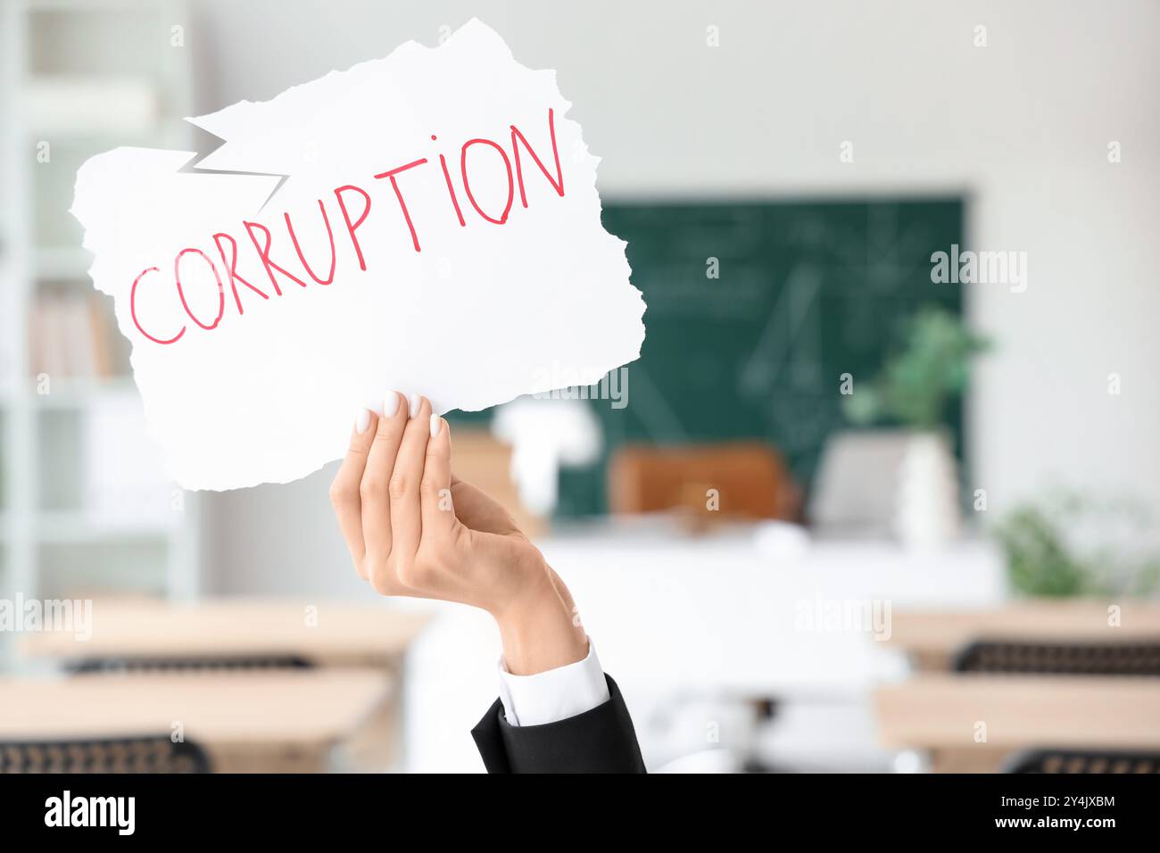 Female teacher holding paper with word CORRUPTION in classroom, closeup ...