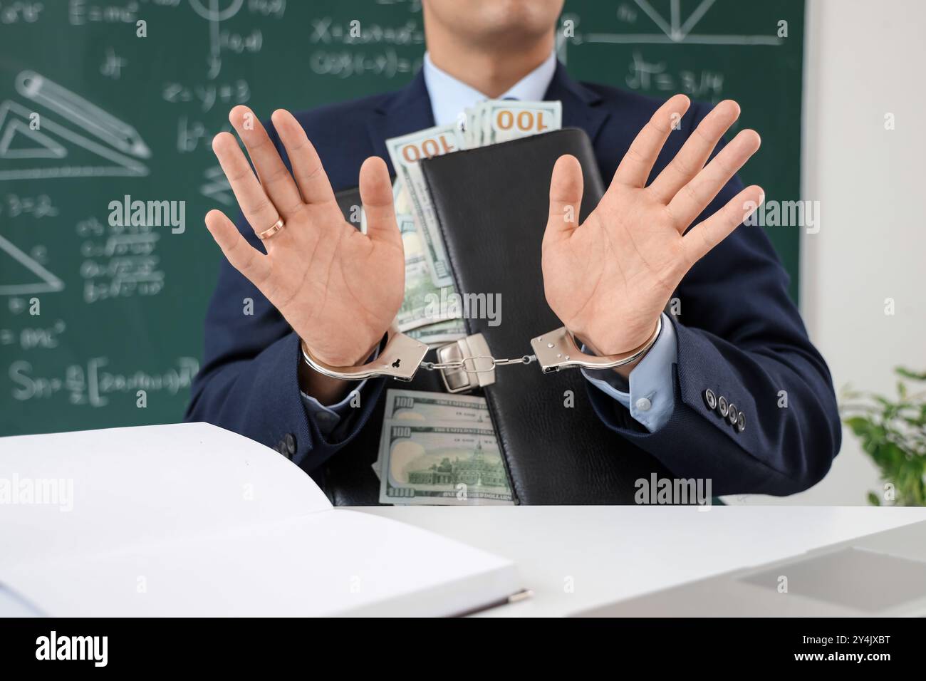 Handcuffed male teacher with briefcase and bribe in classroom, closeup ...