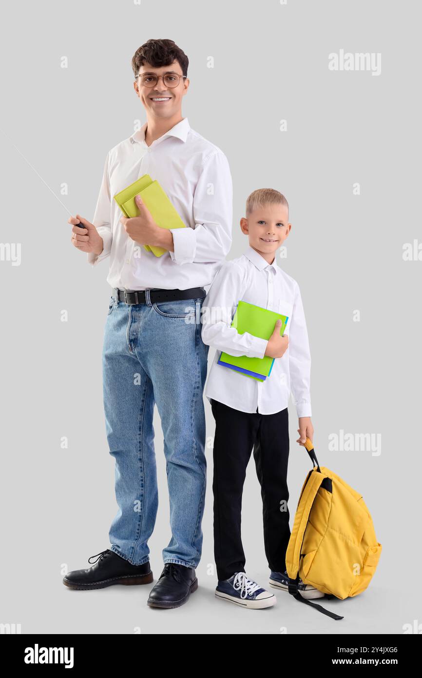 Male teacher with books and little schoolboy on light background Stock ...